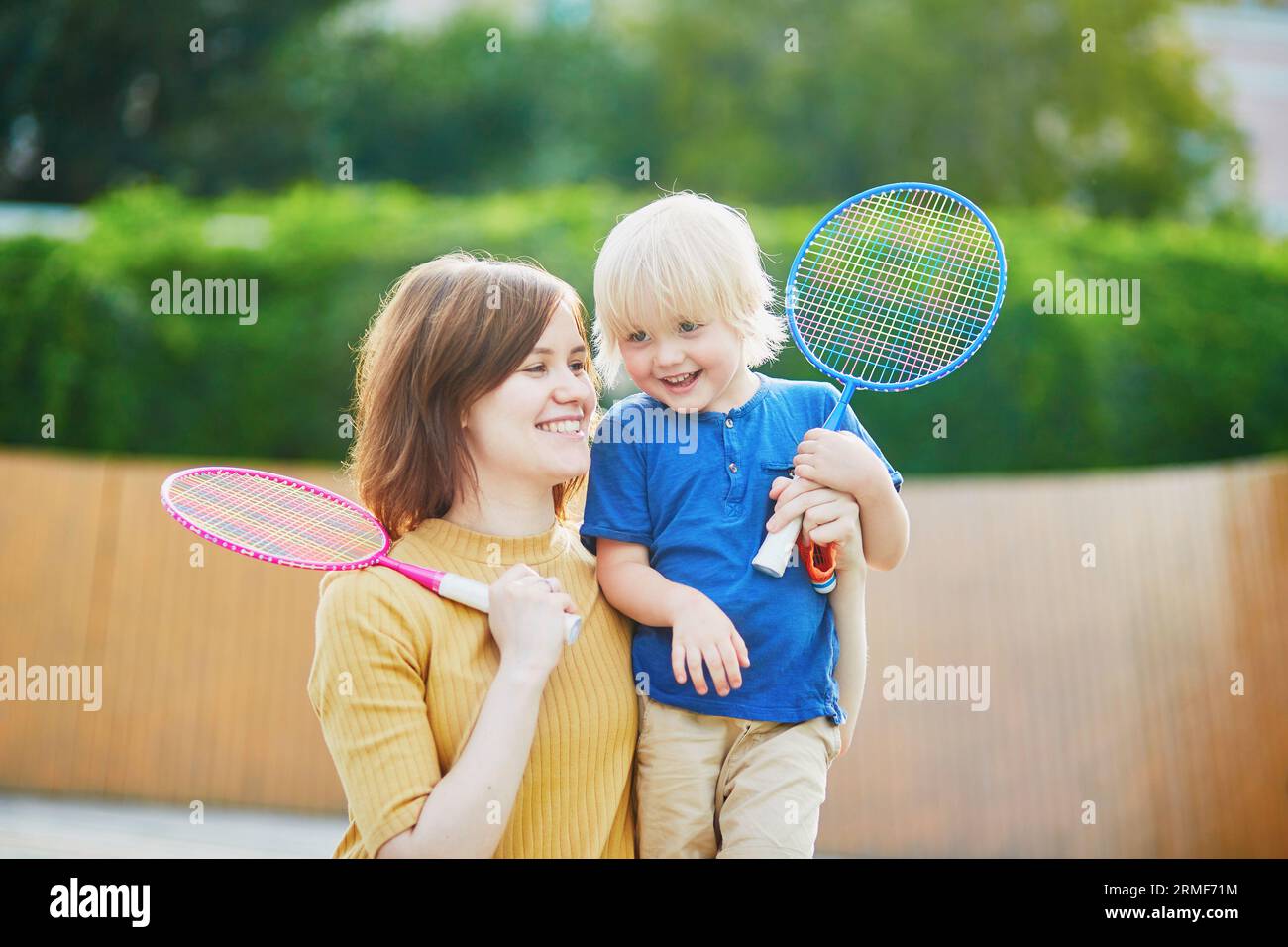 Adorable little boy playing badminton with his mother on the playground ...