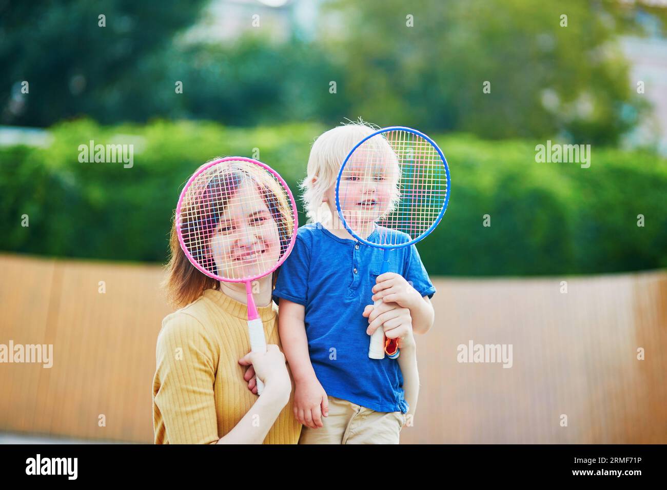 Adorable little boy playing badminton with his mother on the playground ...