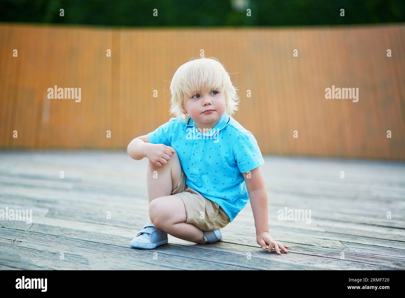Cute little boy squatting on his haunches on the playground Stock Photo ...