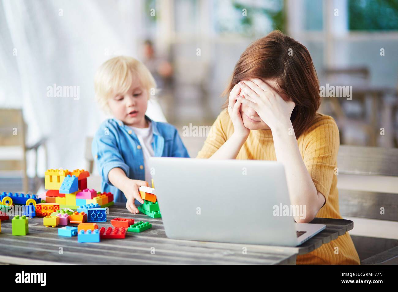Adorable little boy playing with colorful plastic construction blocks ...