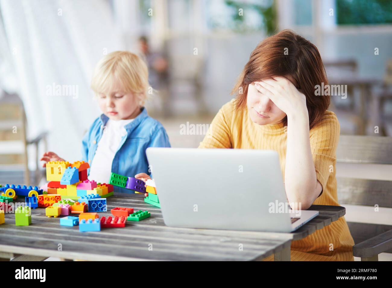 Adorable little boy playing with colorful plastic construction blocks ...