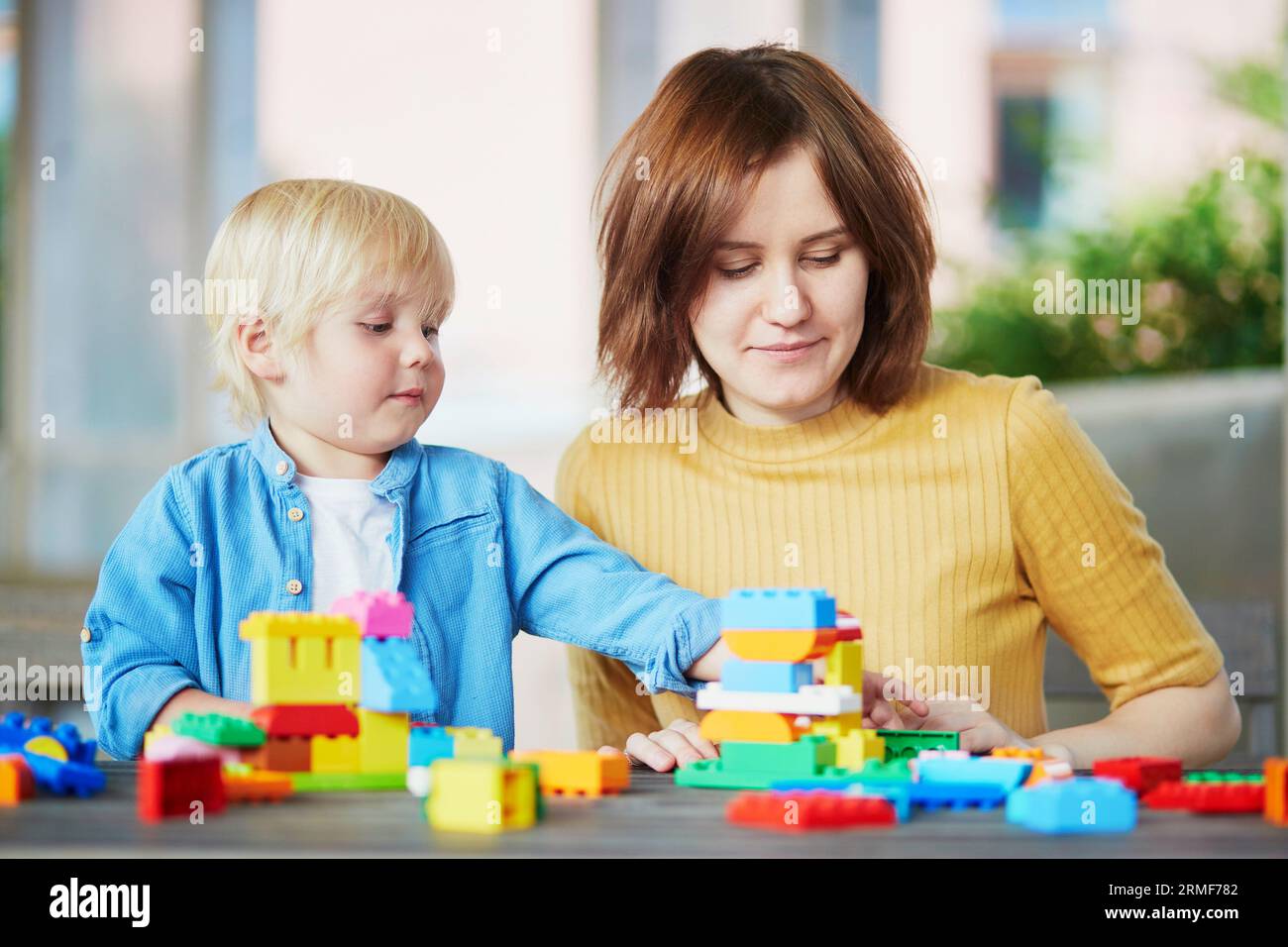 Young mother playing colorful construction blocks with her son. Quality ...