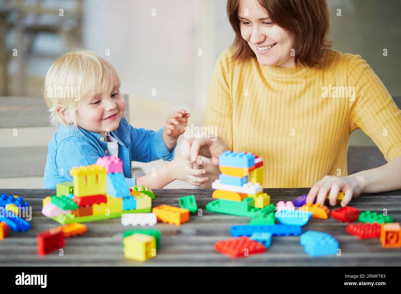 Young mother playing colorful construction blocks with her son. Quality ...