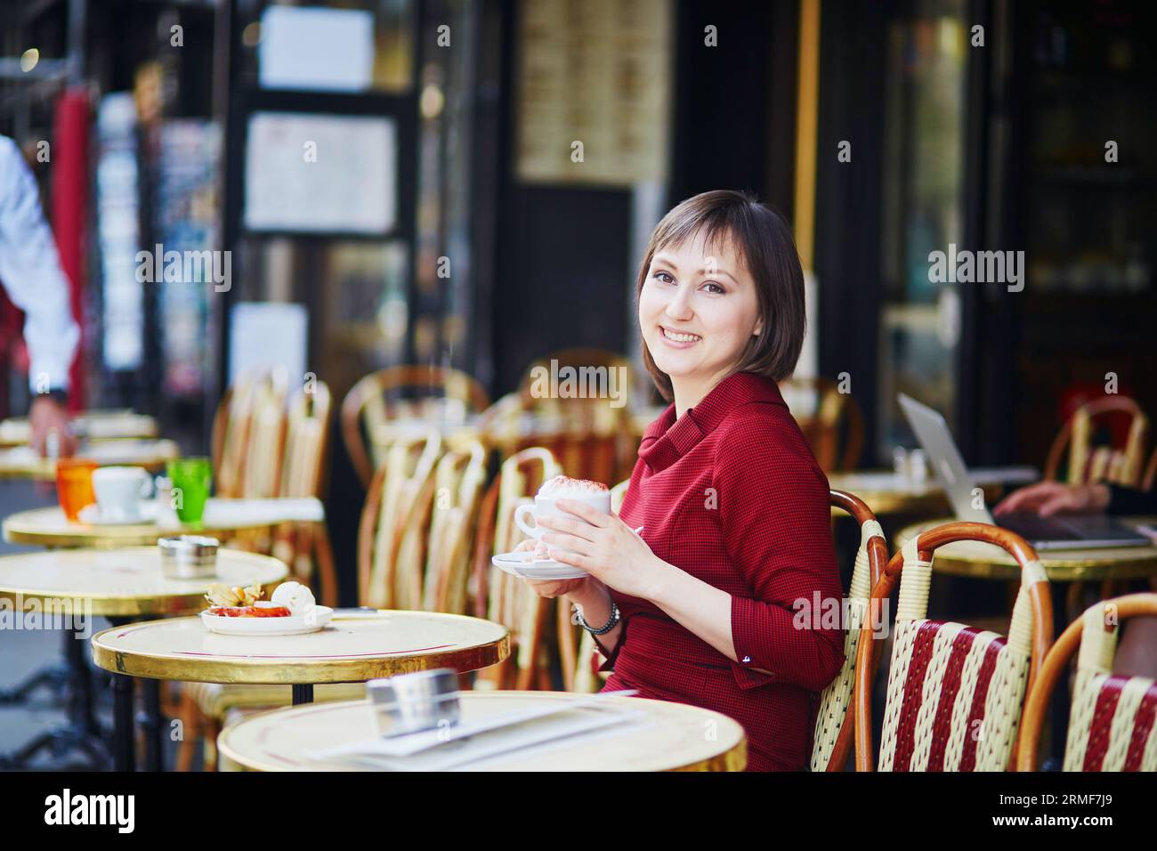 Beautiful young French woman drinking coffee in traditional Parisian ...