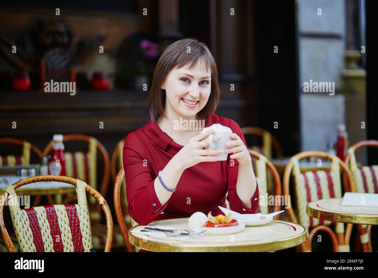 Beautiful young French woman drinking coffee in traditional Parisian ...