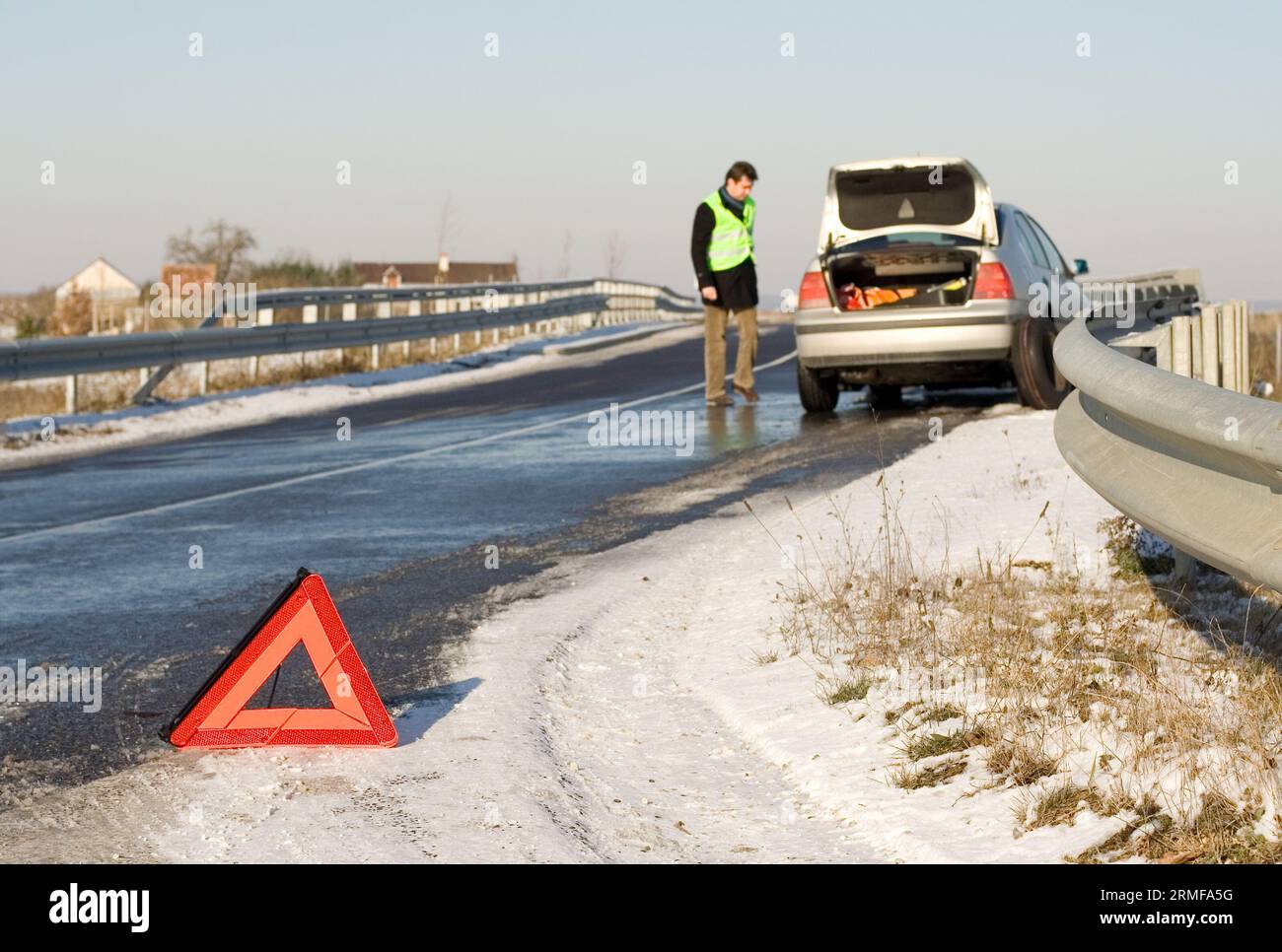 Road accident. Warning triangle and driver in a reflective safety vest ...