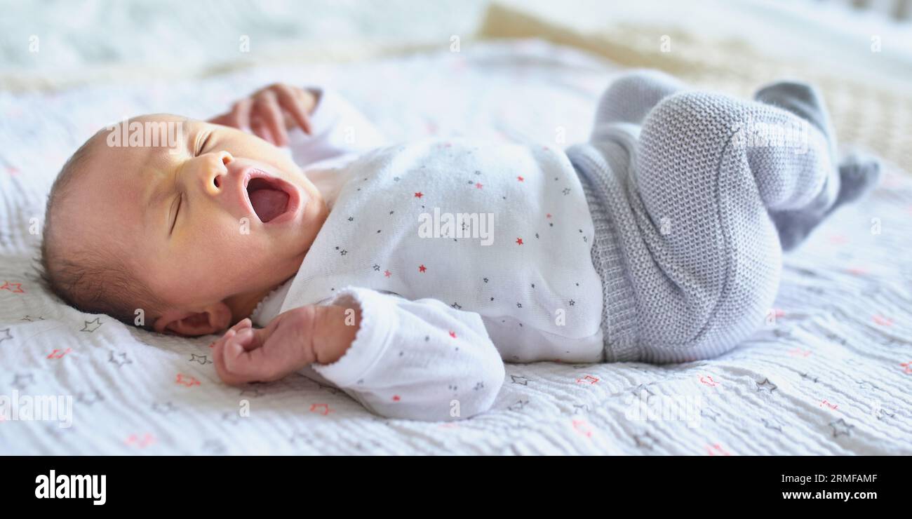 Adorable newborn baby girl sleeping and yawning in bed at home Stock Photo - Alamy