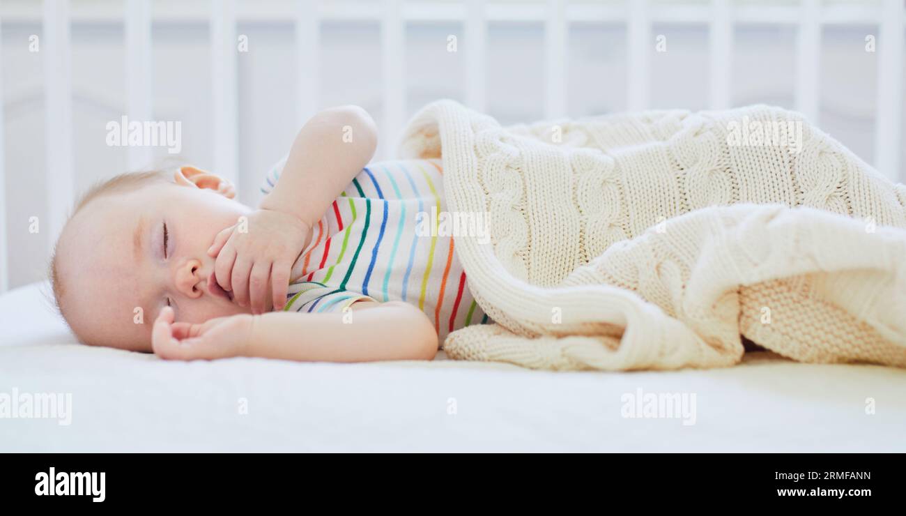 Adorable baby girl sleeping in co-sleeper crib attached to parents' bed ...