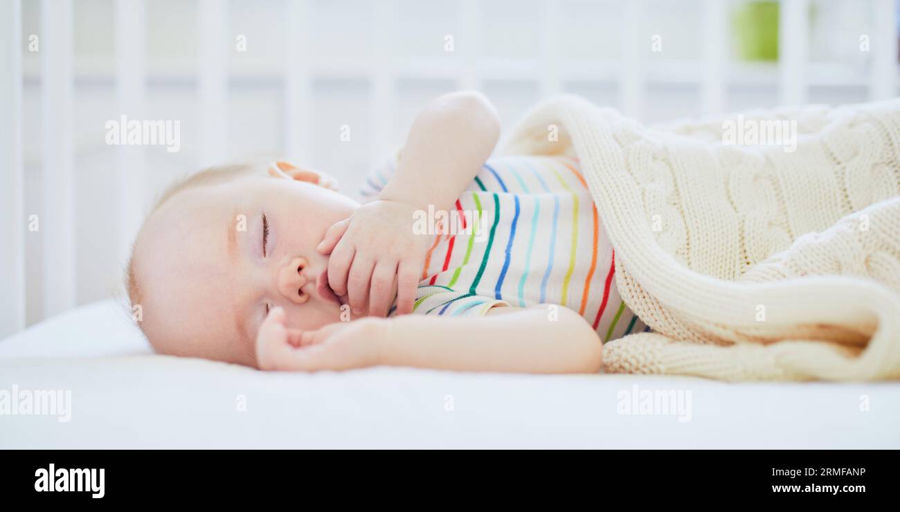 Adorable baby girl sleeping in co-sleeper crib attached to parents' bed ...