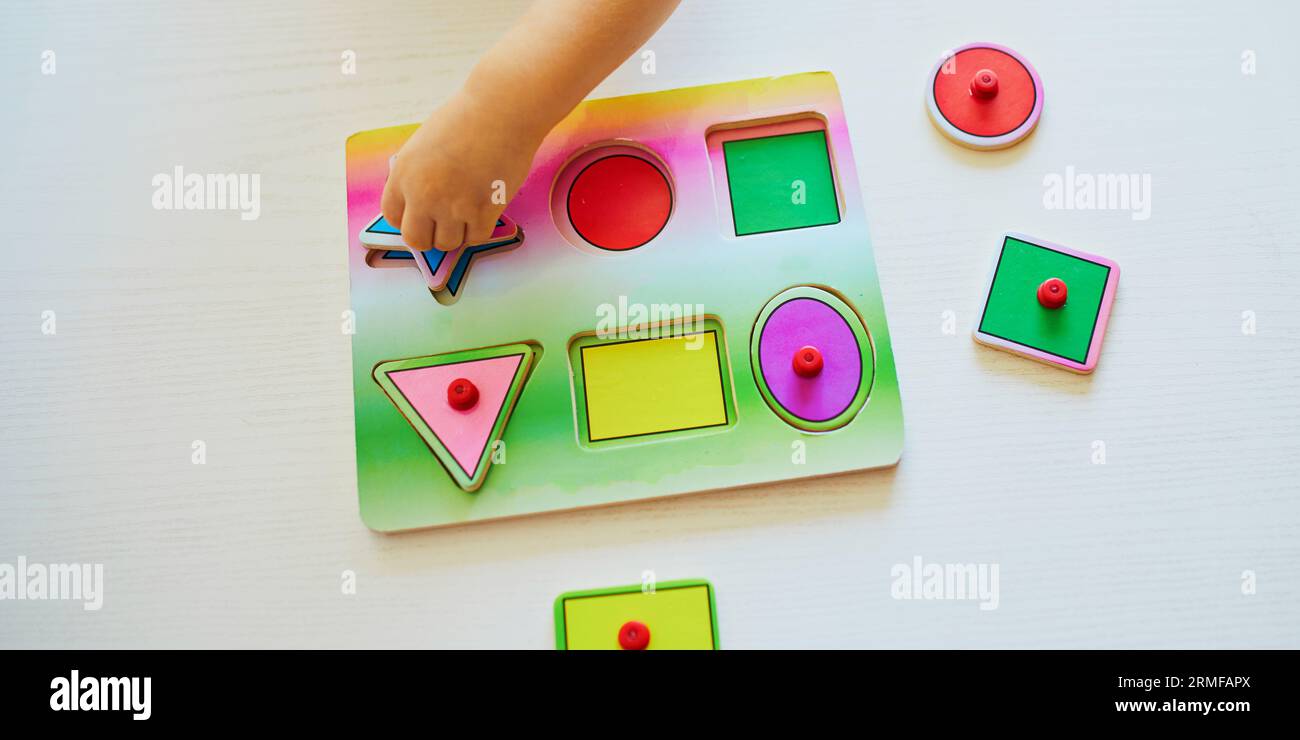 Toddler girl or boy doing wooden puzzle. Child learning geometric ...
