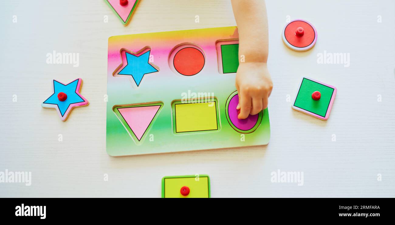 Toddler girl or boy doing wooden puzzle. Child learning geometric ...