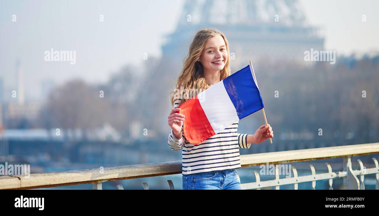 Beautiful young girl with French national tricolor flag near the Eiffel ...