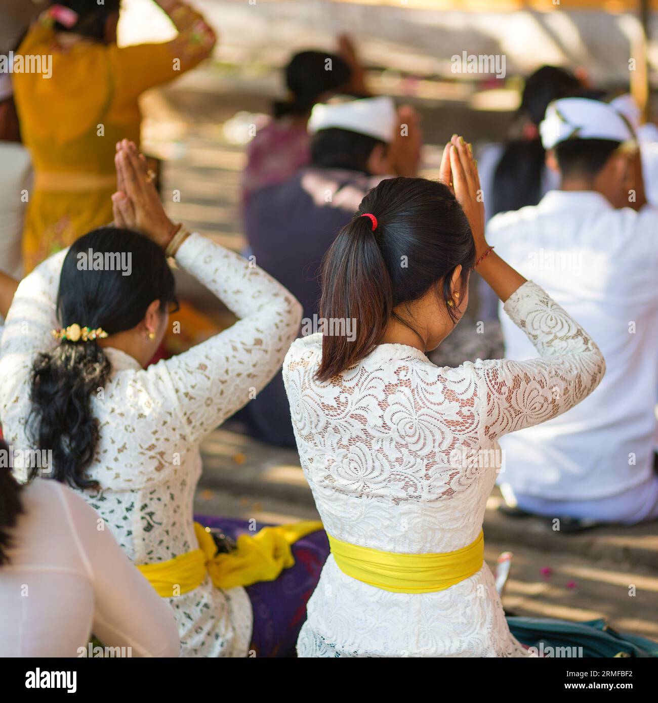 Young Balinese women praying in a temple during ceremony Stock Photo ...