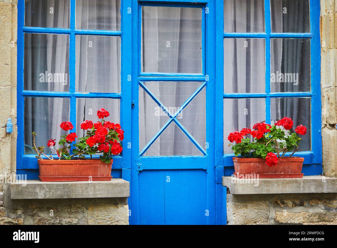 Building decorated with red geranium flowers in medieval town of Vitre ...