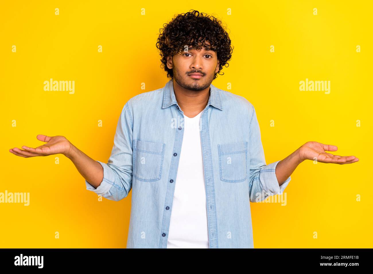 Photo of indifferent handsome man with curly hairdo dressed denim shirt ...