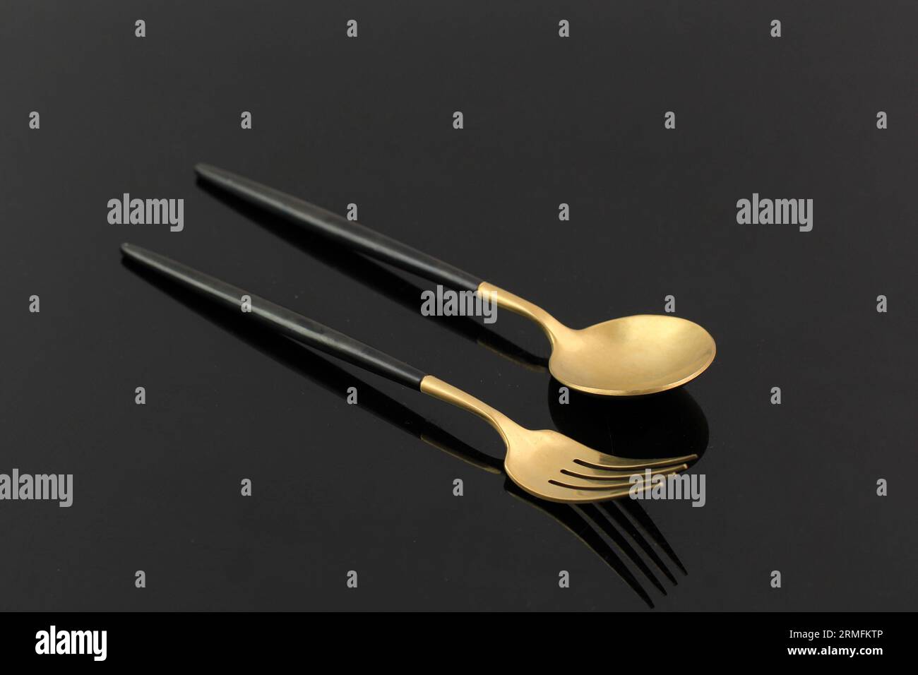 Golden Spoon and Fork Isolated on Black Table Stock Photo - Alamy
