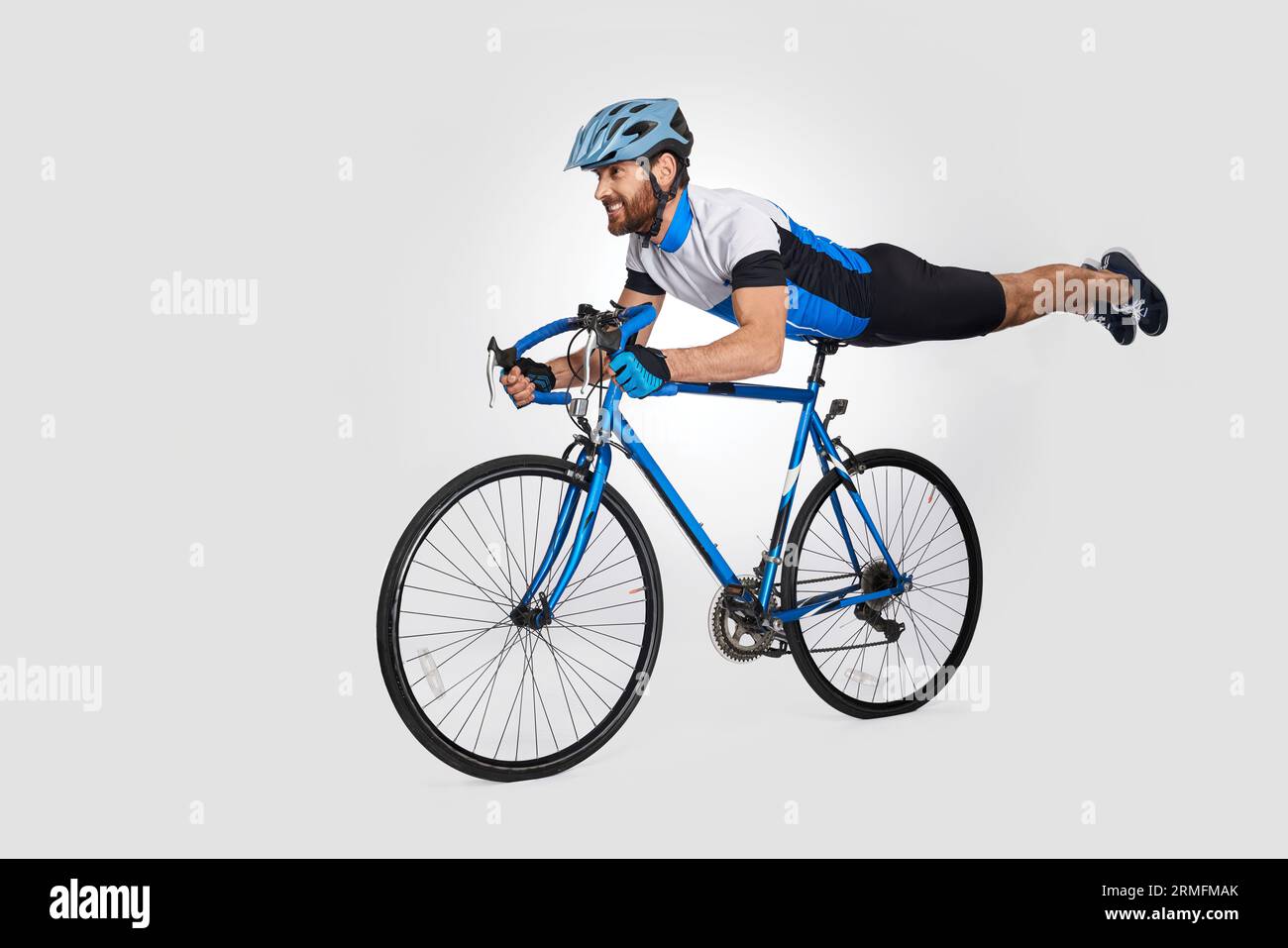 Strong middle aged cyclist doing trick on bike, while riding. Side view ...