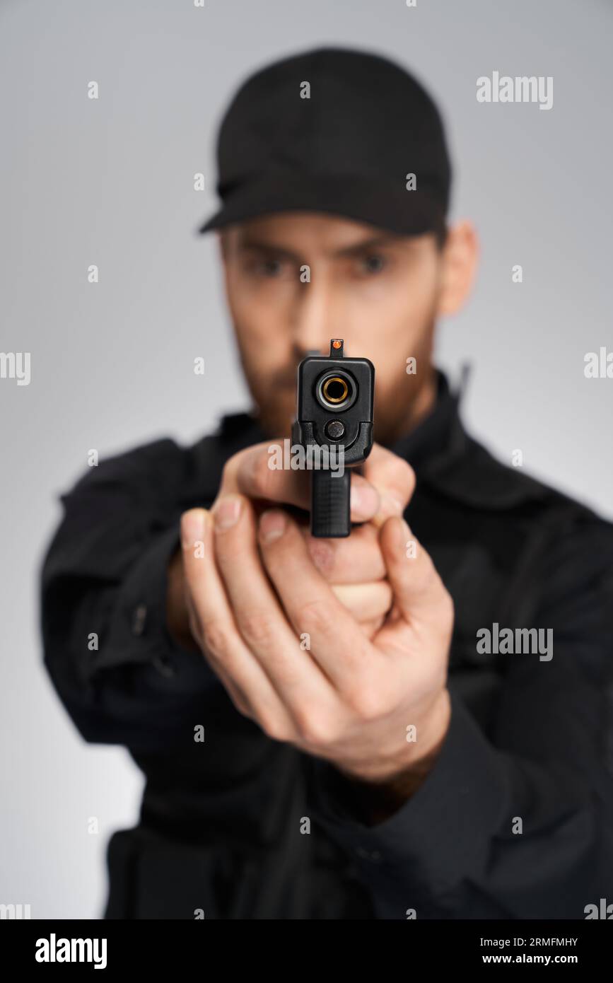 Unrecognizable cop in uniform taking aim, focused on camera indoors ...