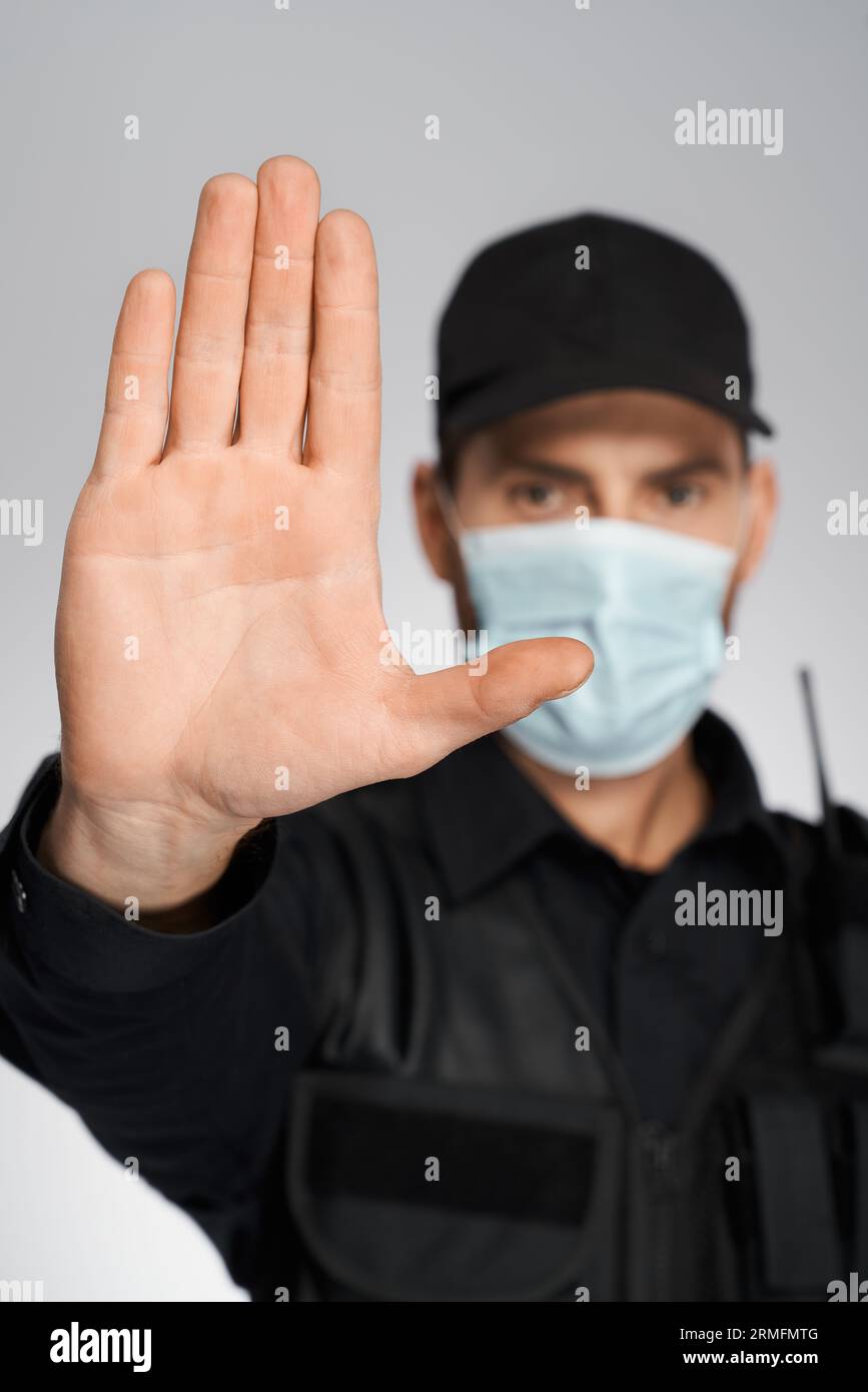 Young man wearing police uniform showing stop sign with palm of hand ...