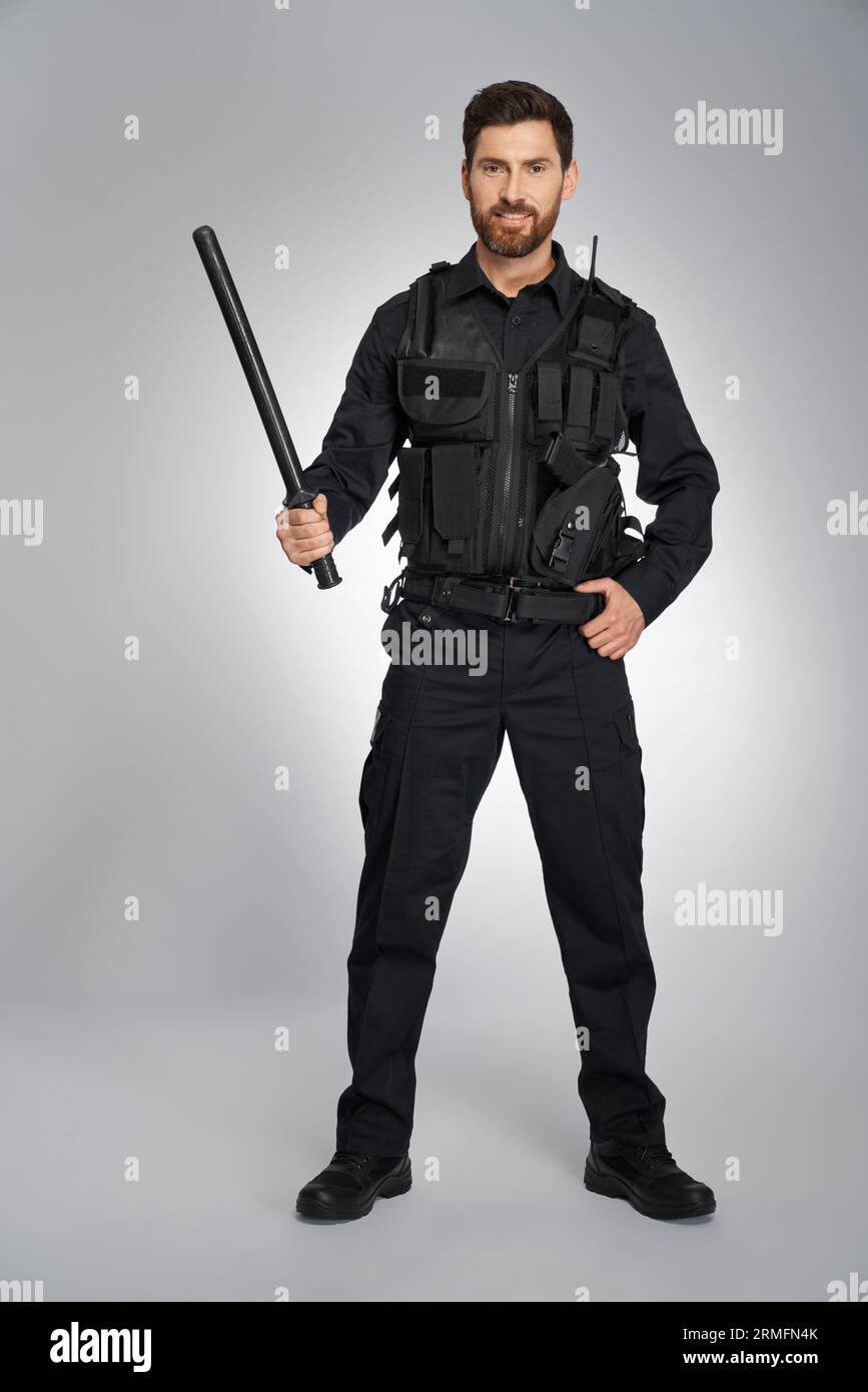 Smiling handsome officer with black baton posing to camera. Front view ...