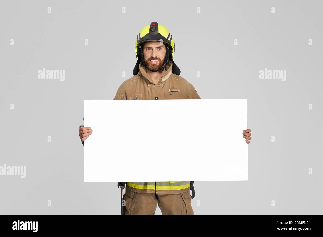 Happy firefighter holding blank banner, while looking at camera in ...