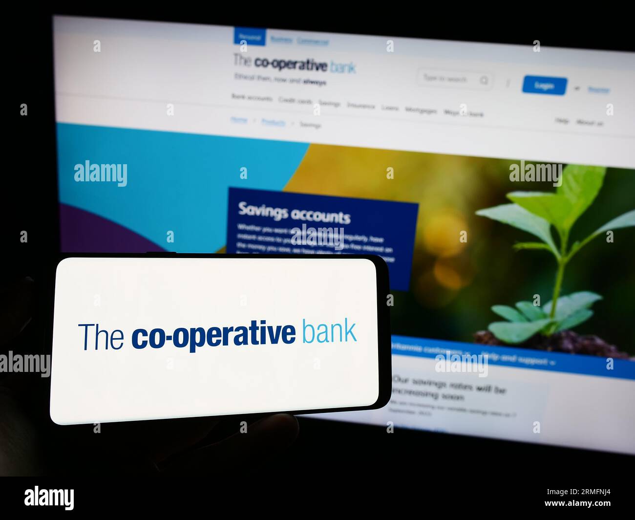 Person holding cellphone with logo of British company The Co-operative Bank plc on screen in ...