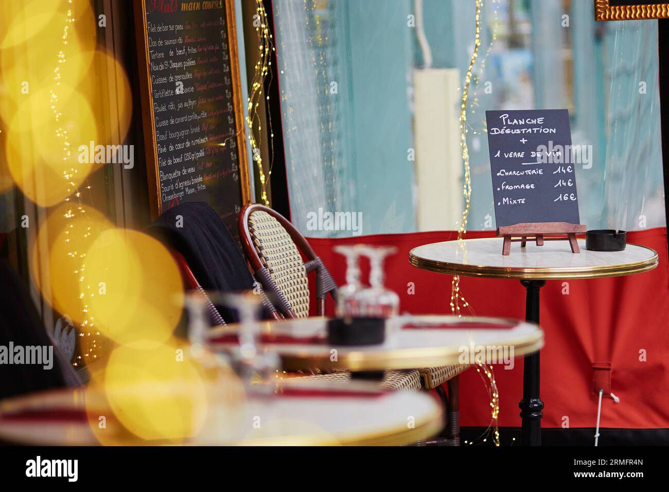 Cozy Parisian outdoor cafe with yellow lights and menu board on the ...