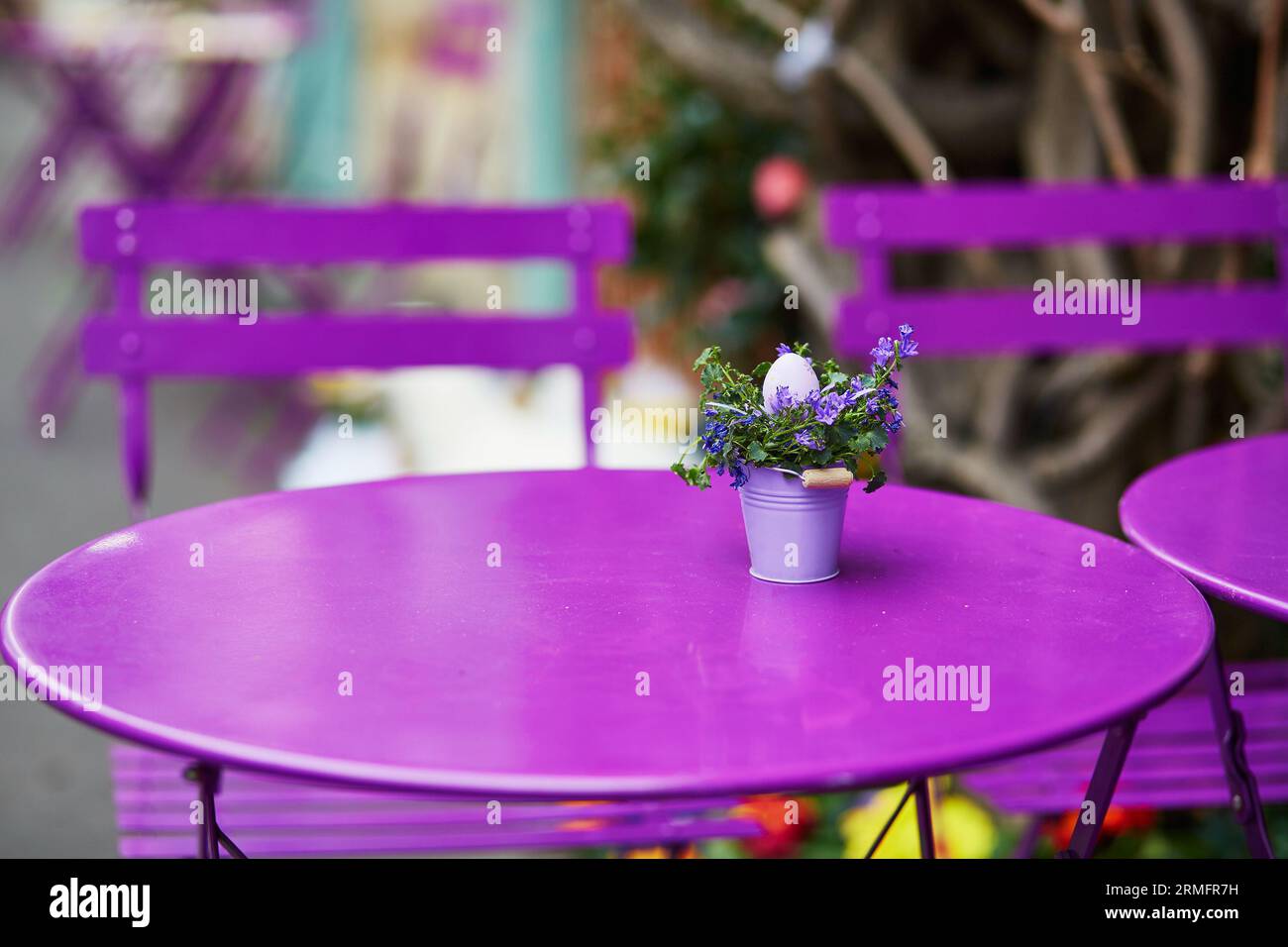 Purple table of Parisian outdoor cafe decorated with little bucket ...