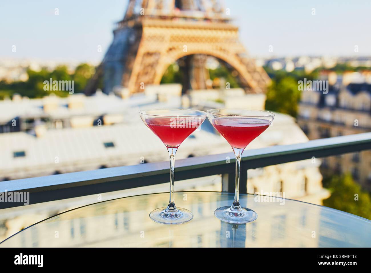 Two Cosmopolitan cocktails in traditional martini glasses on a glass ...