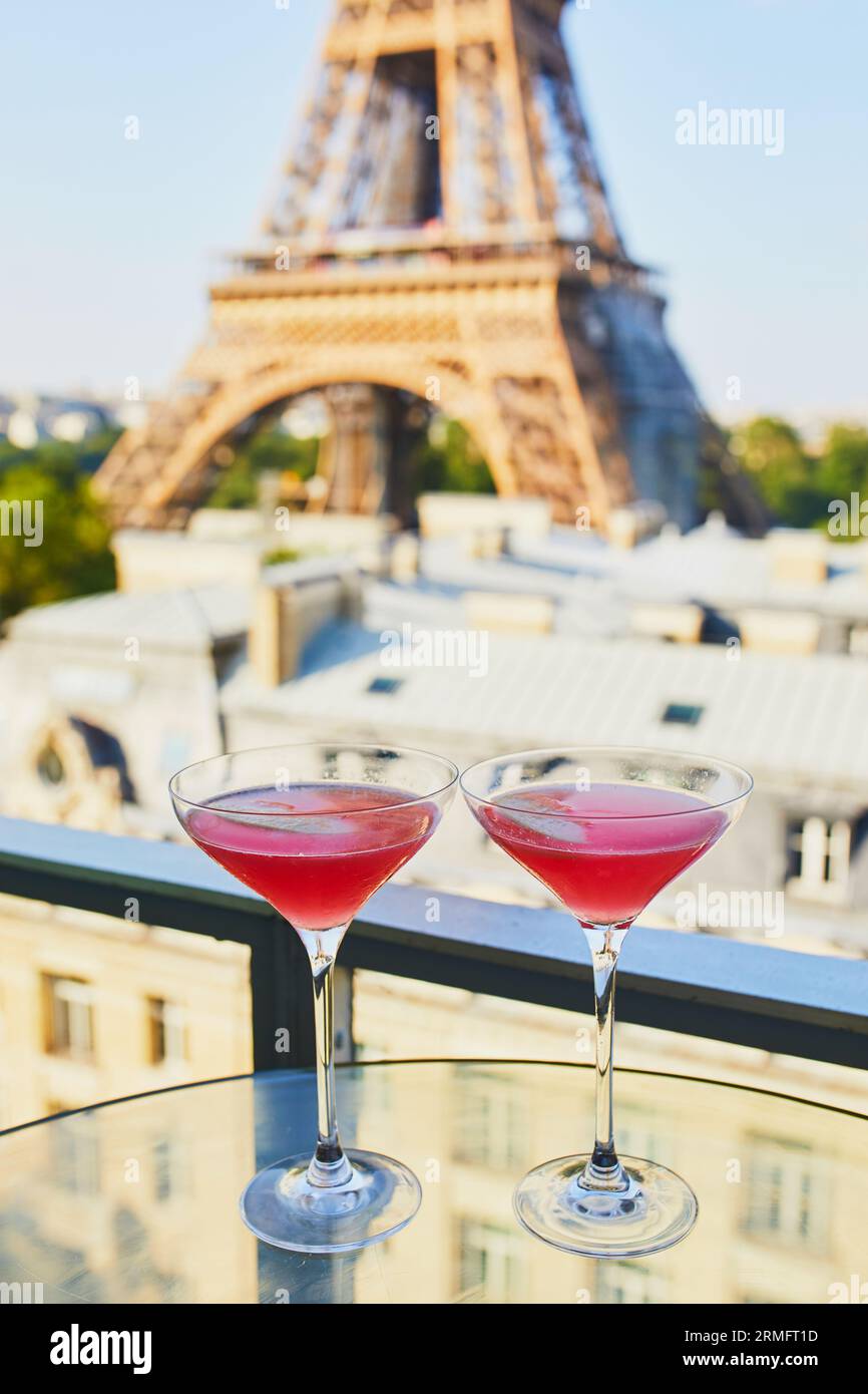 Two Cosmopolitan cocktails in traditional martini glasses on a glass ...