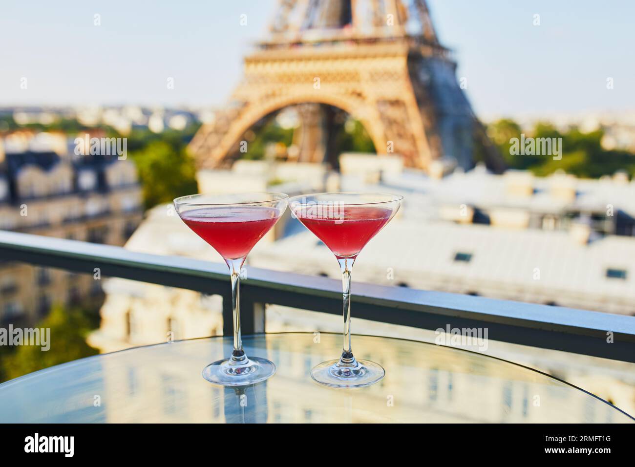 Two Cosmopolitan cocktails in traditional martini glasses on a glass ...