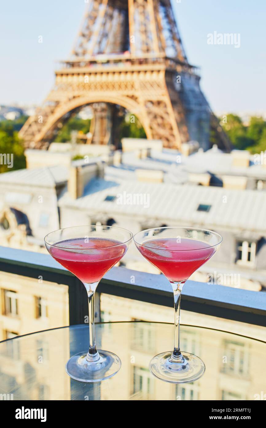 Two Cosmopolitan cocktails in traditional martini glasses on a glass ...