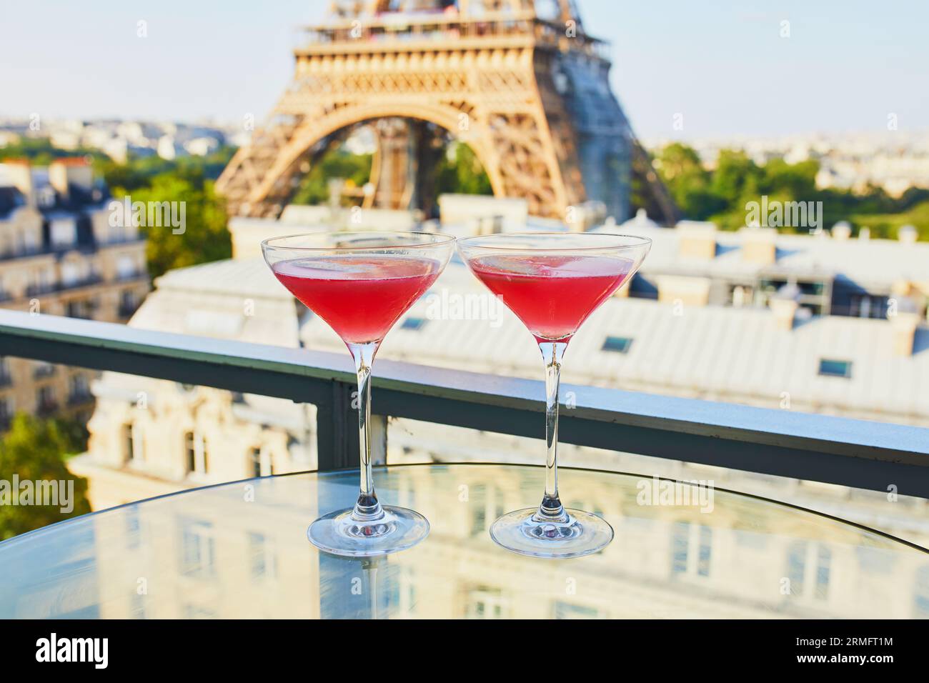 Two Cosmopolitan cocktails in traditional martini glasses on a glass ...