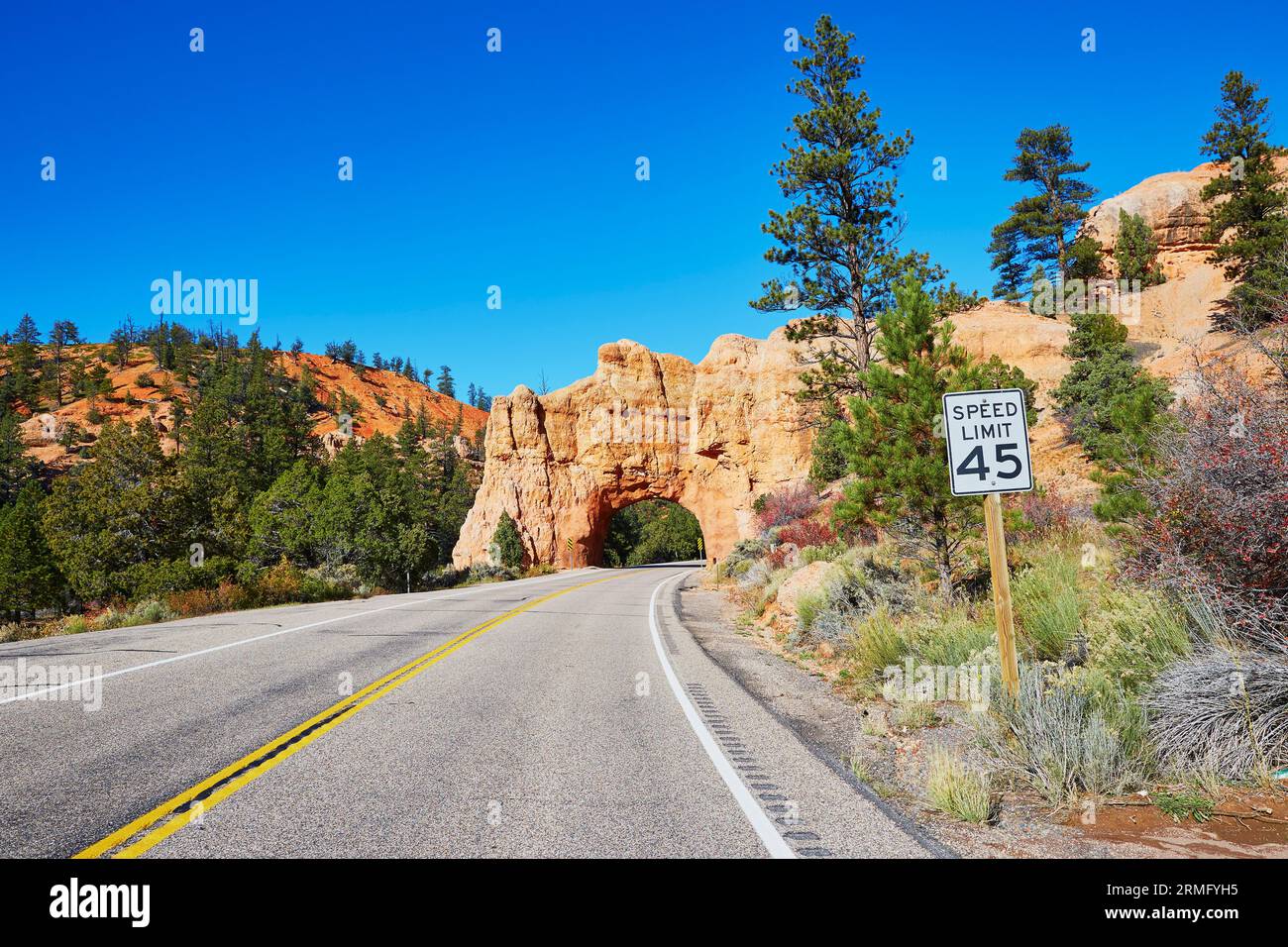 Scenic view of stunning red sandstone natural bridge and asphalt road ...