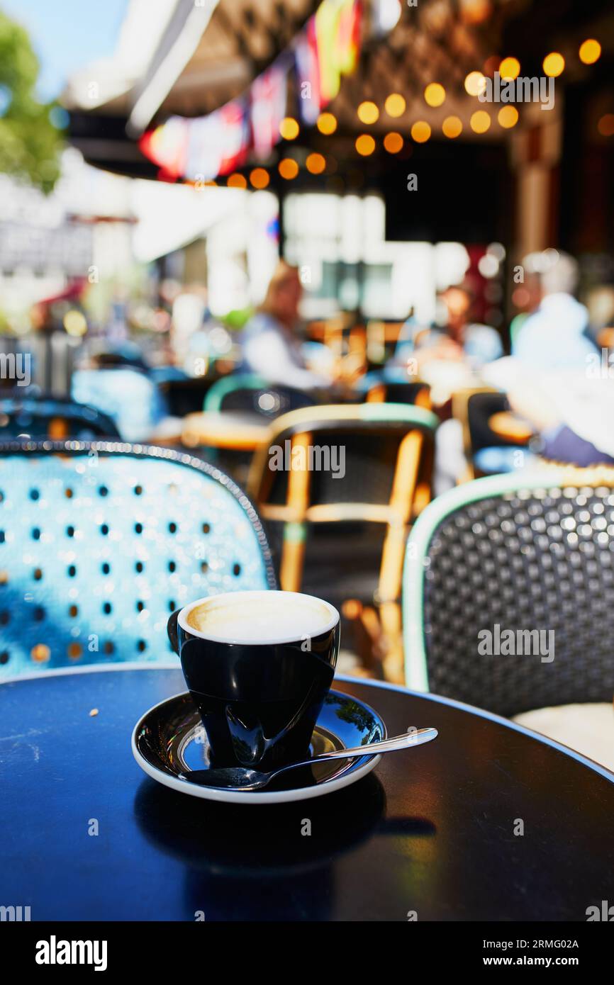 Cup of coffee on the table of traditional French street cafe in Paris ...