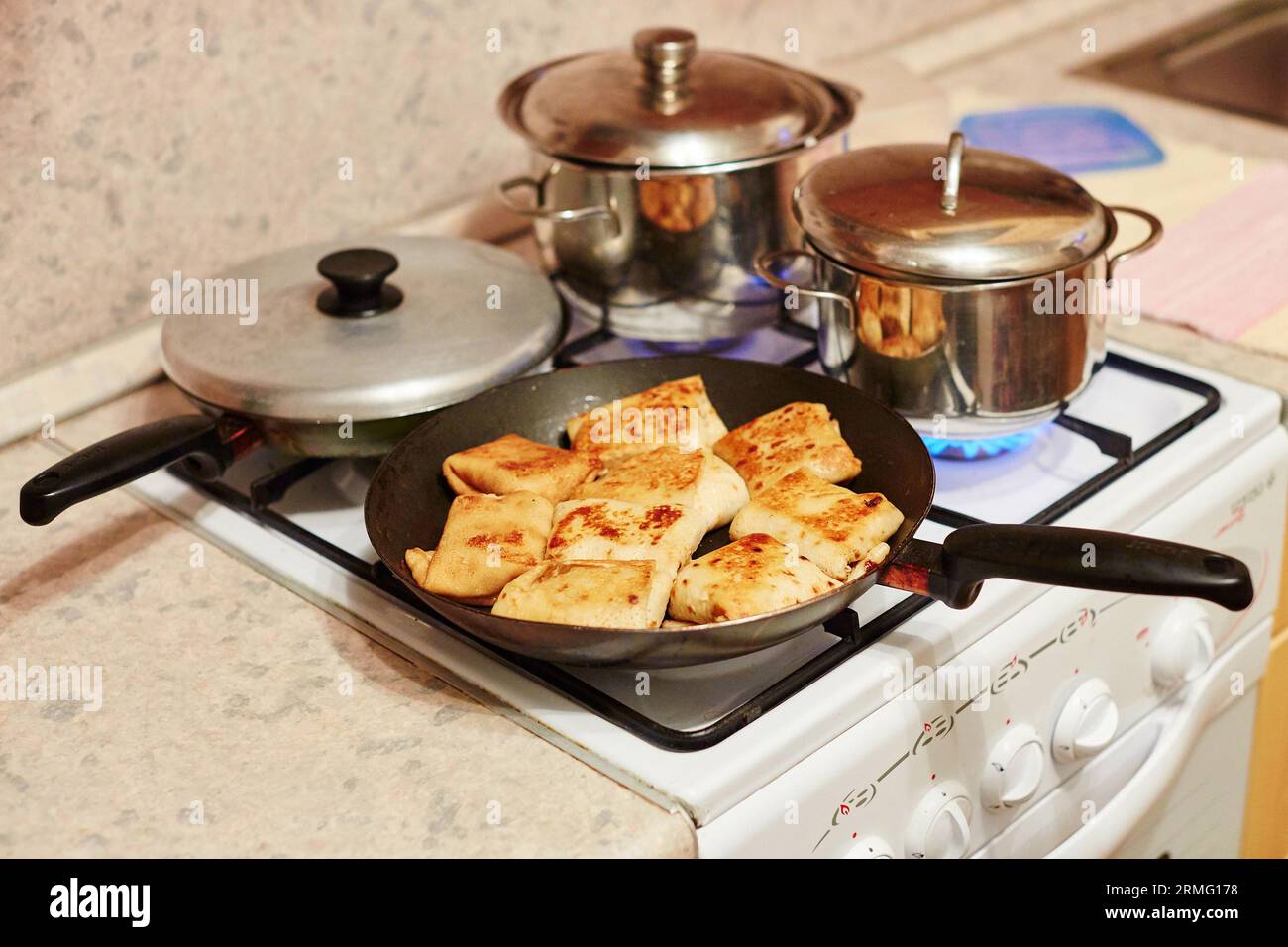 Traditional Russian fried stuffed pancakes (blini) on a frying pan ...