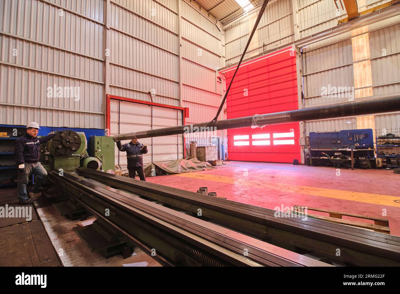 men using a lift and a crane to move big, heavy metal objects like pips ...