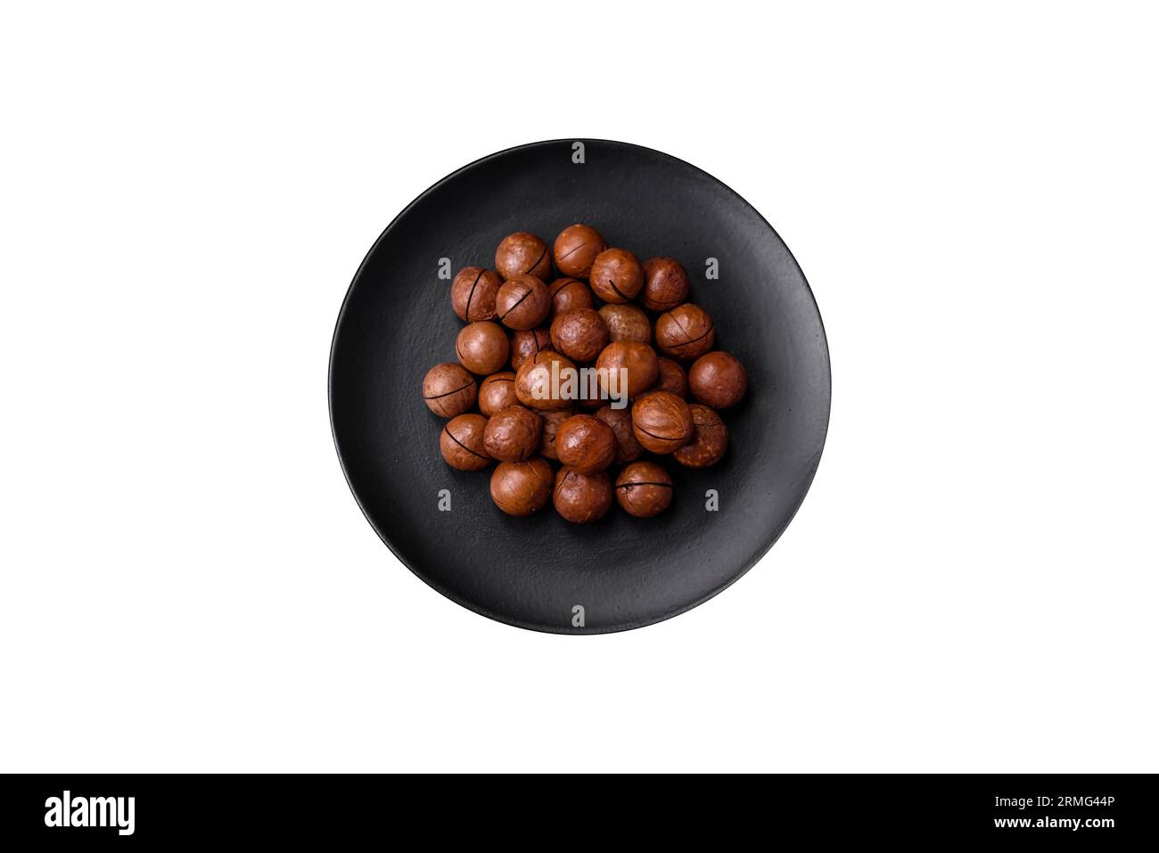 Delicious roasted macadamia nuts in shell on a dark textured concrete ...