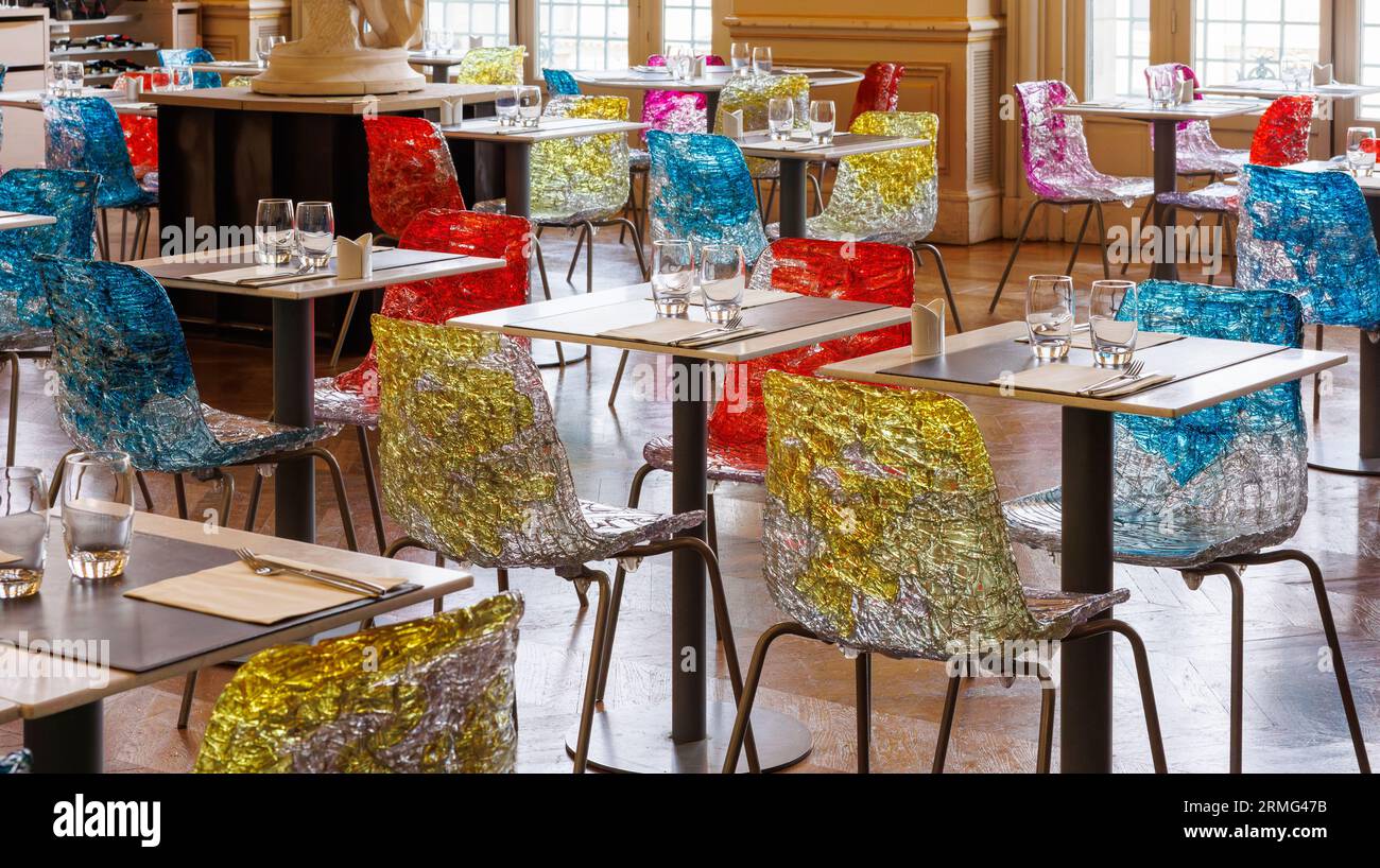 A colorful cafeteria layout with red, yellow, and blue chairs with ...