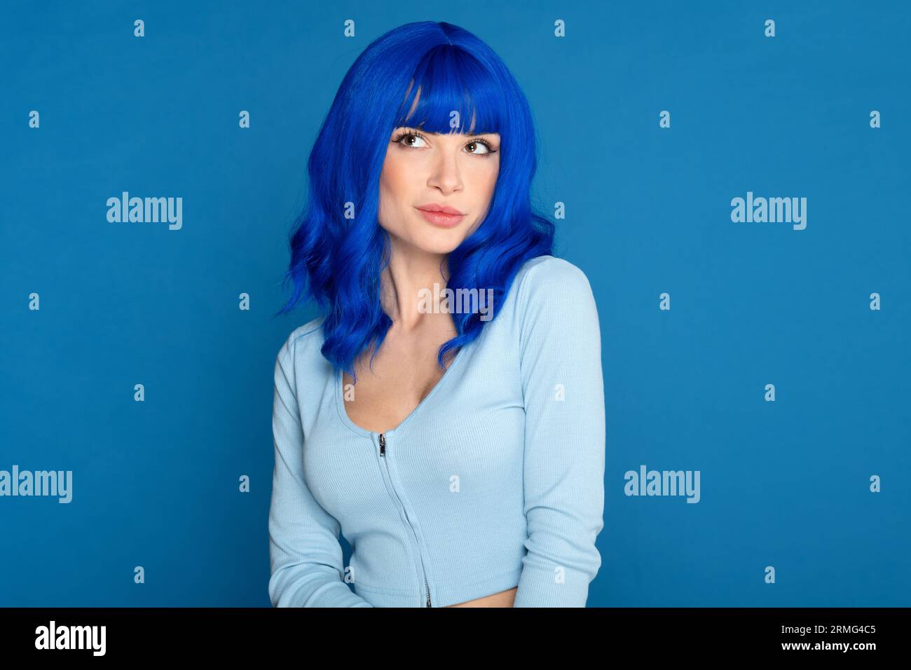 Confident young female model in blue bright wig and casual wear looking ...