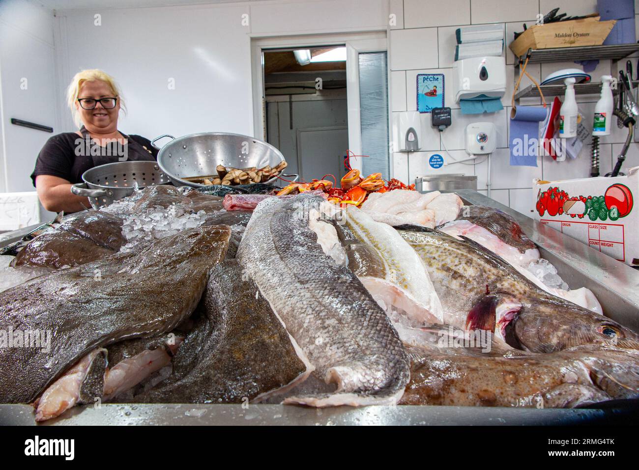 A lady serves very fresh fish in a fishmonger at Dungeness, Kent Stock ...