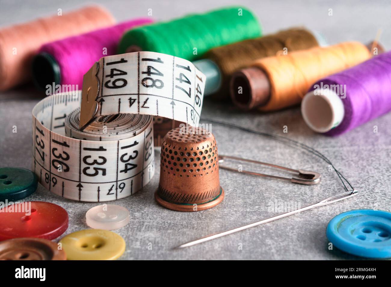 Sewing kit of needle, thimble, thread and measuring meter.On gray ...