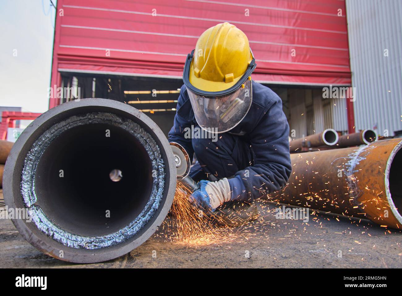 a man in full safety gear like a helmet, visor, and vest. doing welding ...