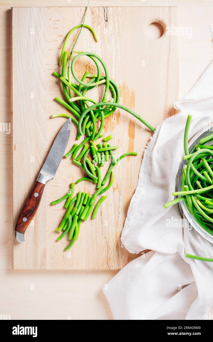 Green garlic scapes on a cutting board, top view Stock Photo - Alamy
