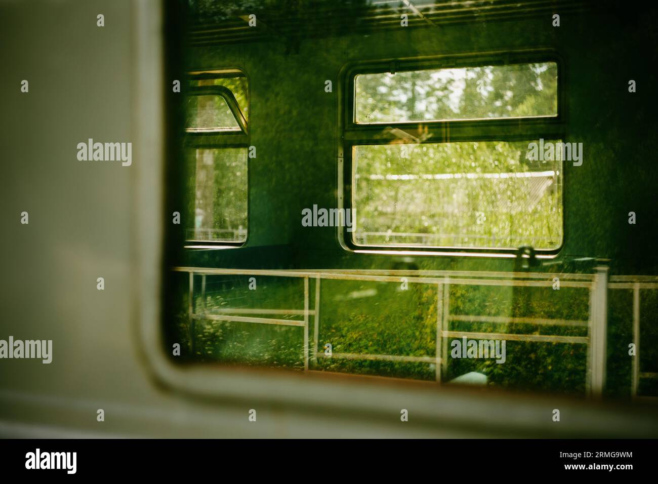 The windows of an old electric train reflecting the greenery of trees ...