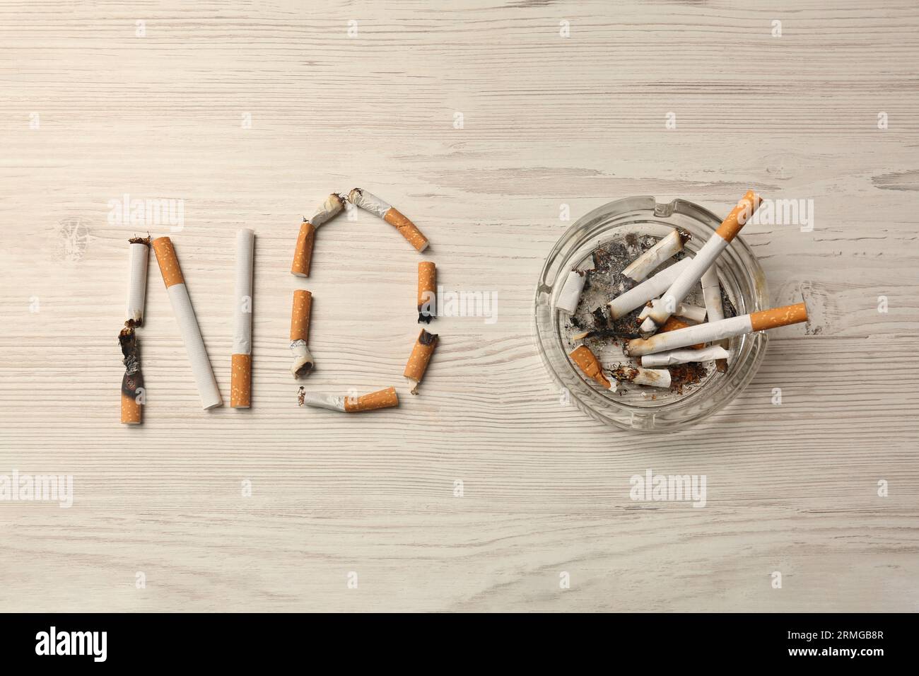 Word No made with burnt cigarettes and ashtray on white wooden table ...