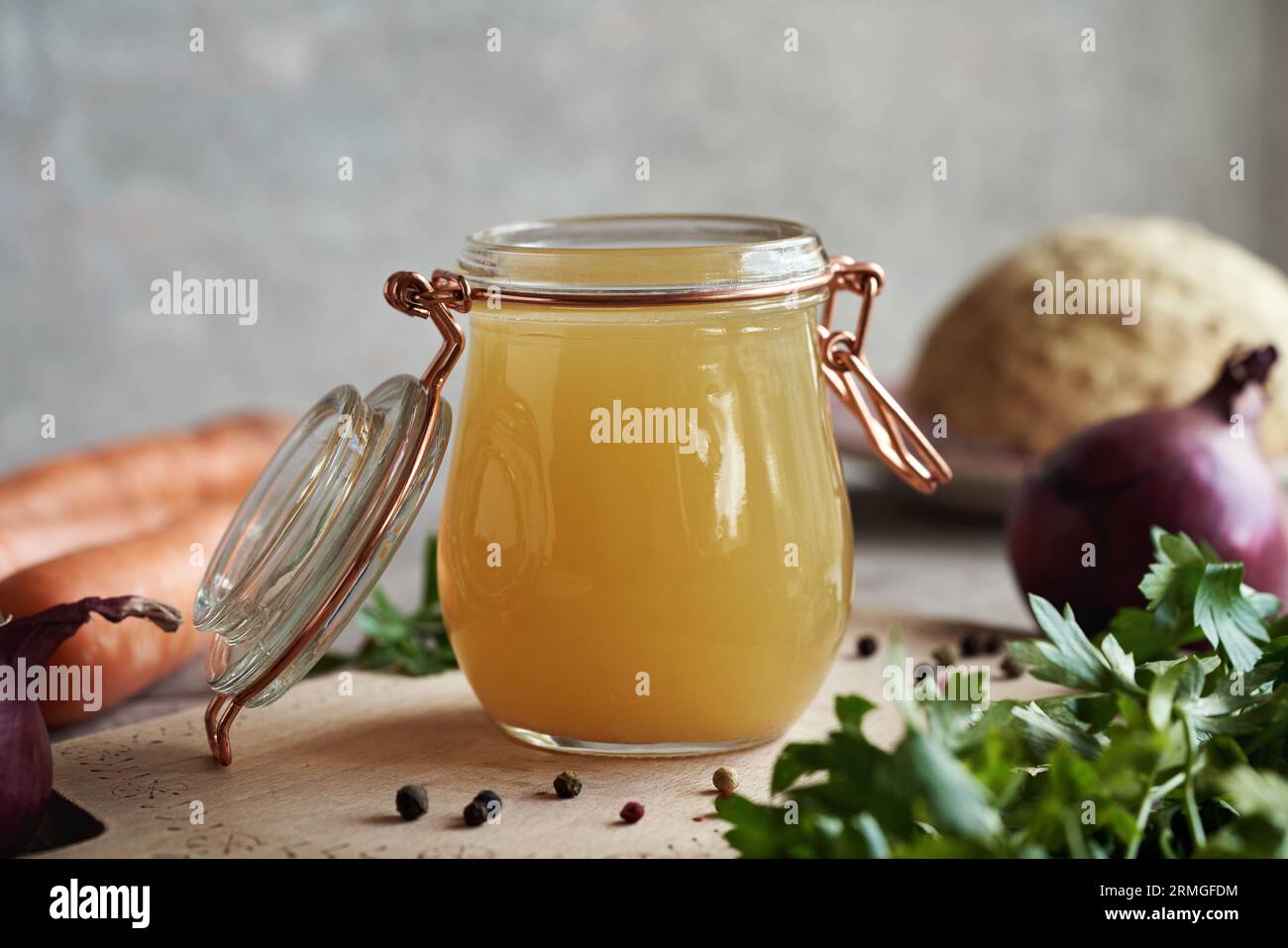 Chicken bone broth in a glass jar with parsley, carrots, onion and ...