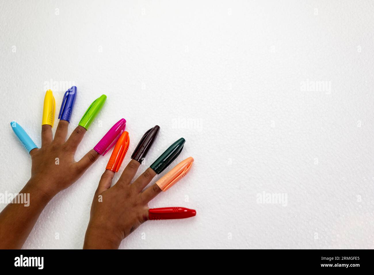 A close-up of ten fingers, each with a colorful pen cap on the end ...