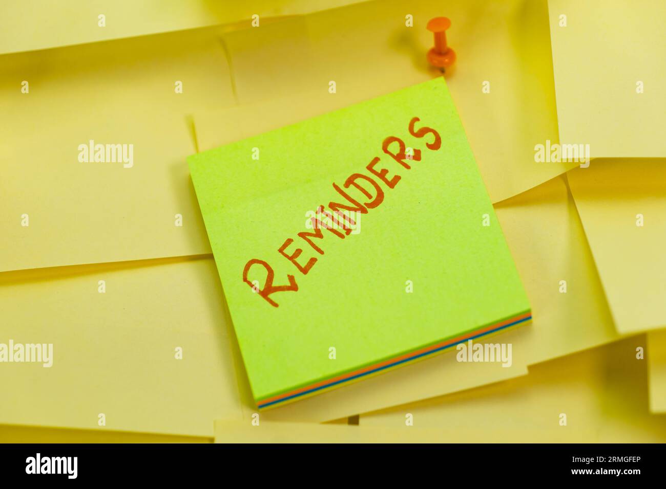 A stack of yellow sticky notes with the word "reminders" written on ...