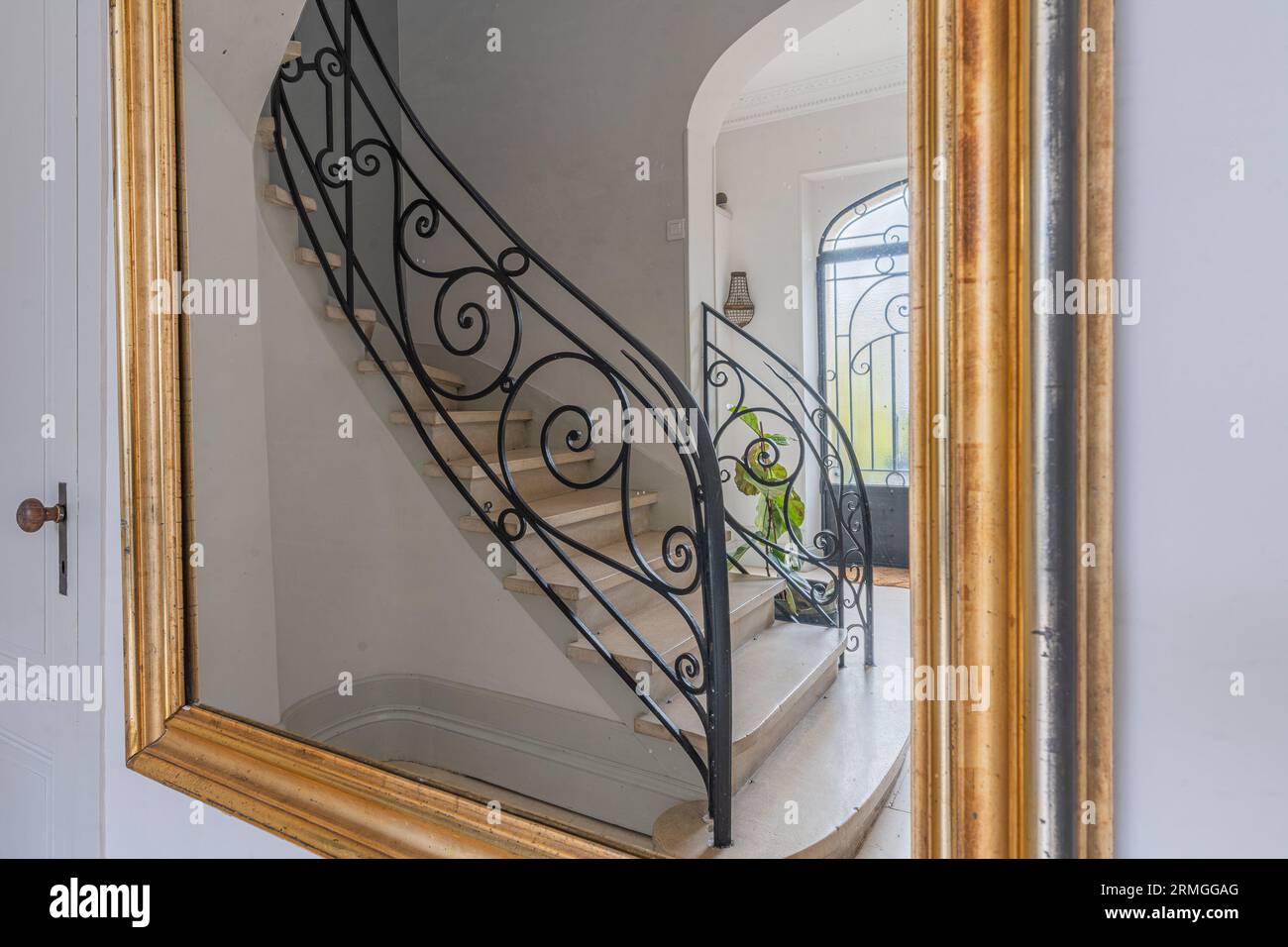 A luxurious gold framed mirror elegantly mounted onto a wooden banister ...